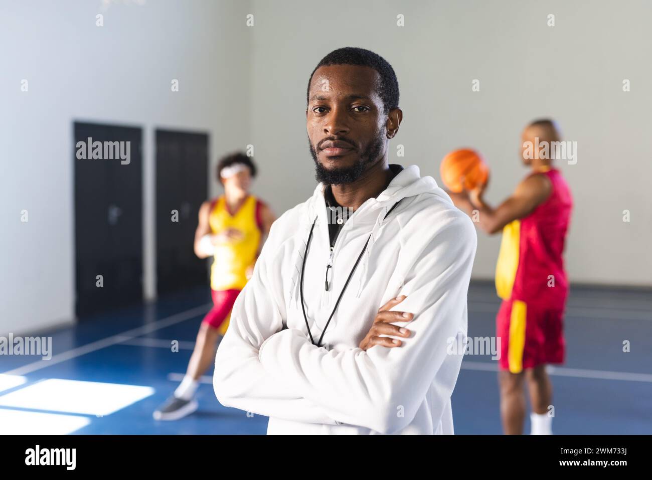 African American coach stands confidently in a gym, arms crossed Stock ...