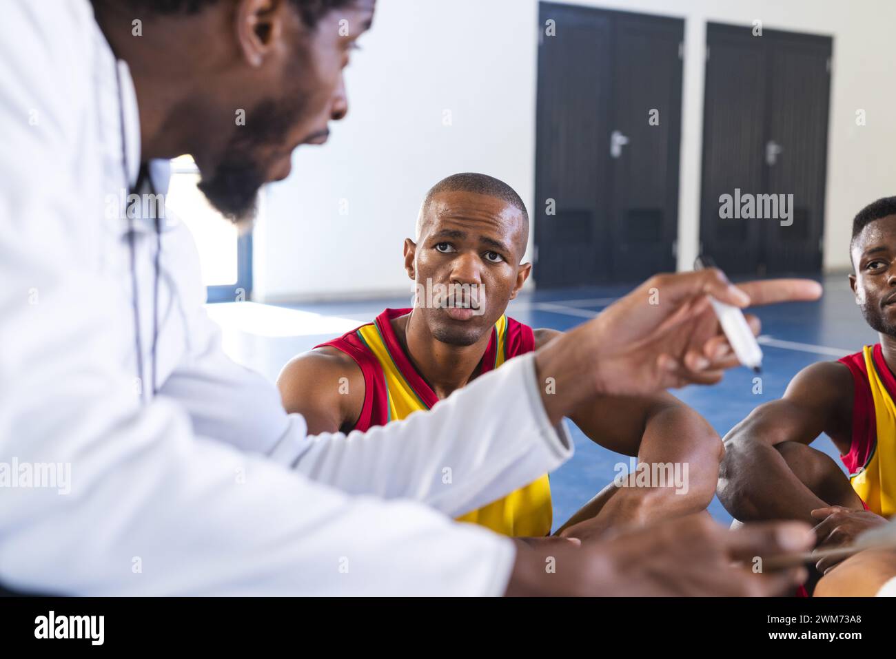 African American coach discussing strategy with players in a gym Stock ...
