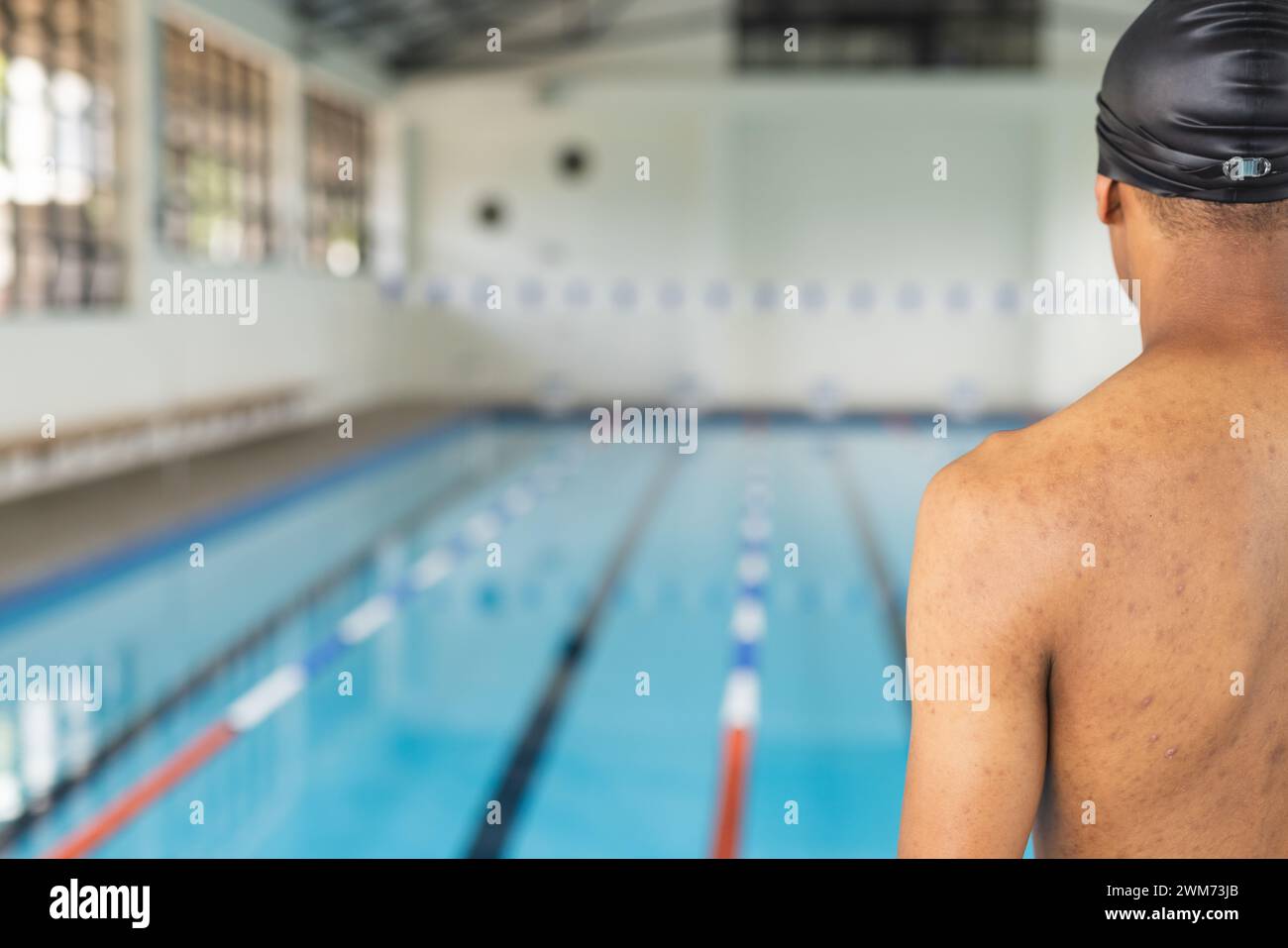 Young biracial male athlete swimmer ready to swim at an indoor pool ...