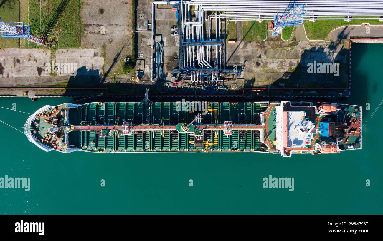 A cargo ship is docked at an industrial port, its structure a complex ...