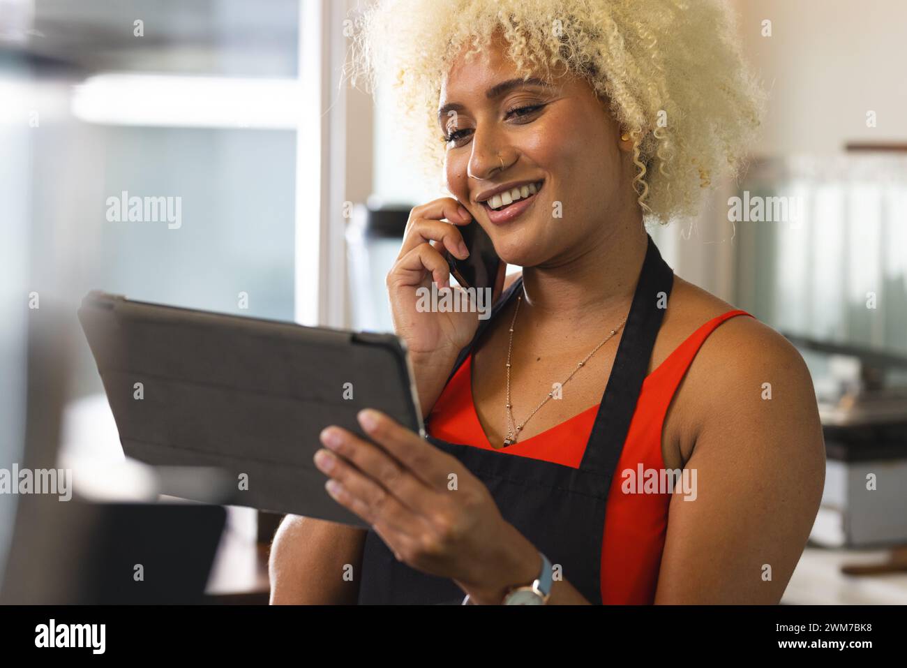 Young biracial female cafe owner barista multitasks in a modern office ...