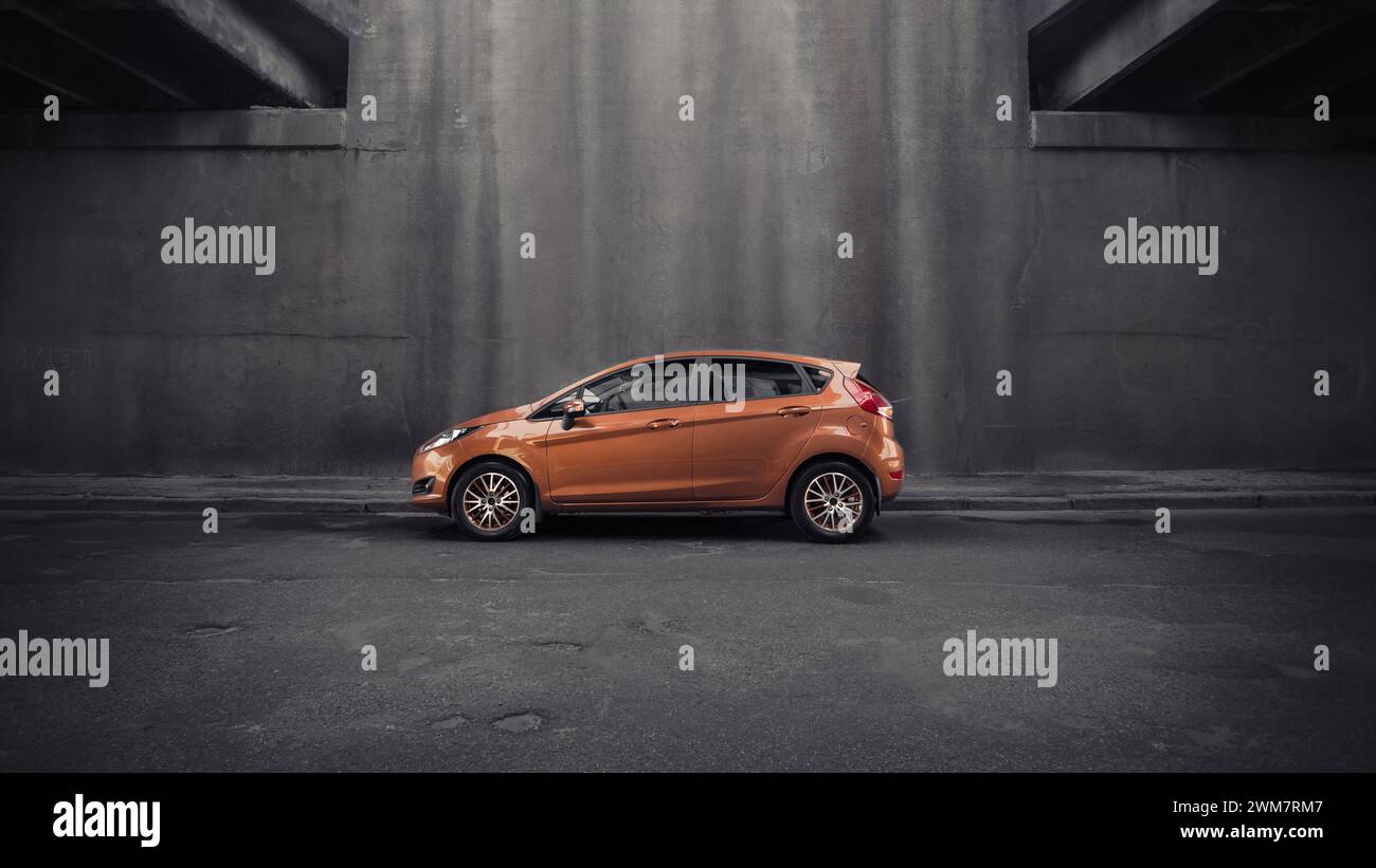 brown Ford Fiesta in front of concrete wall. Side view of compact ...