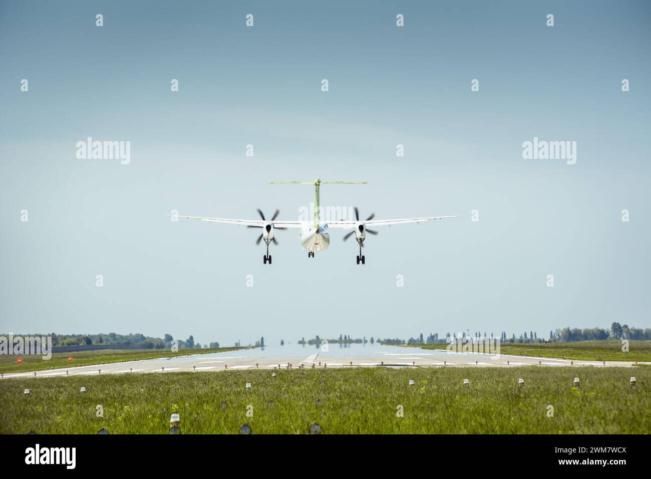 Turboprop aircraft landing on a runway on a sunny day. Two engine ...