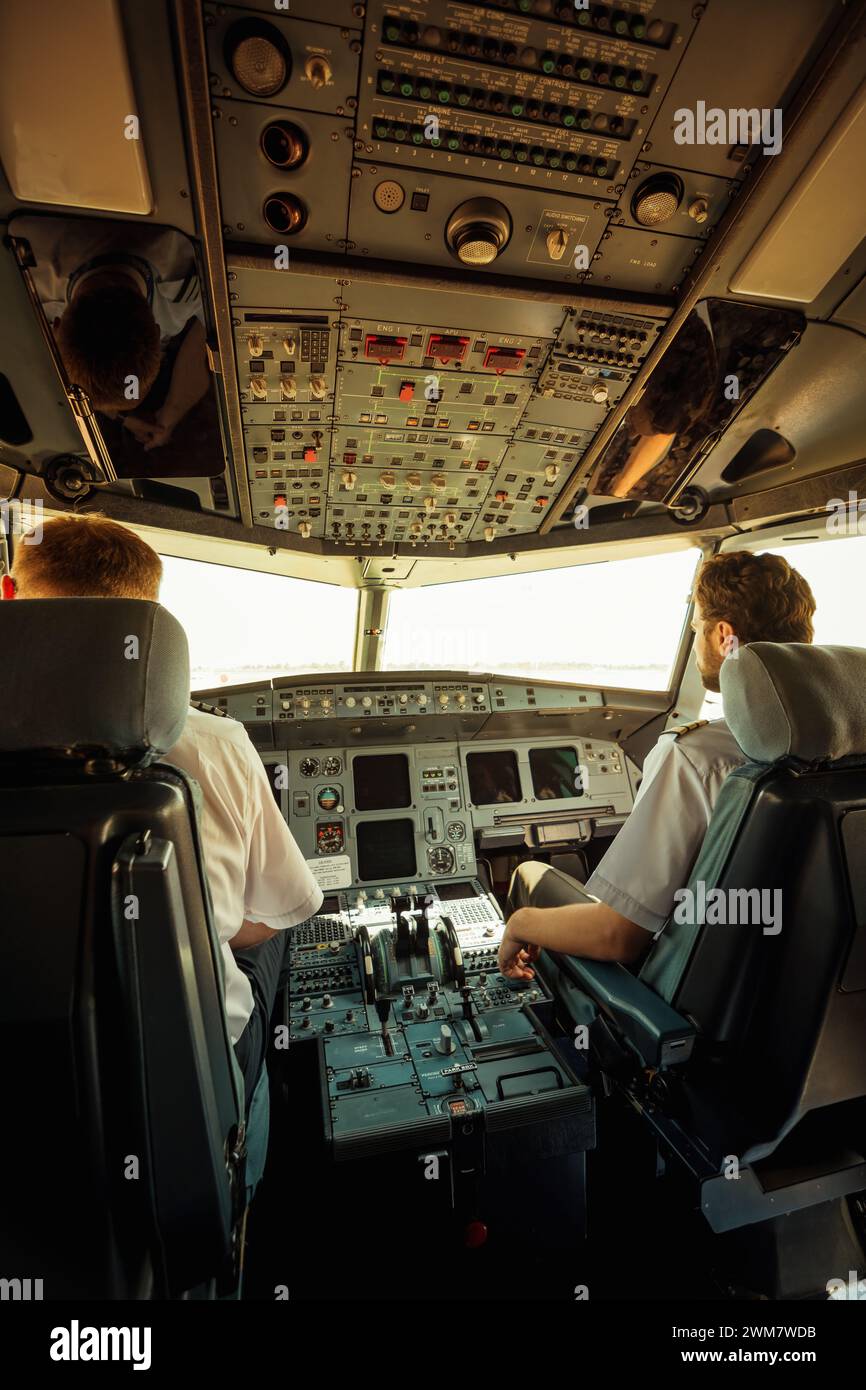 inside pilot's cabin of Airbus A320-212 (registration UR-WRM). Warm toned vertical image of two ...
