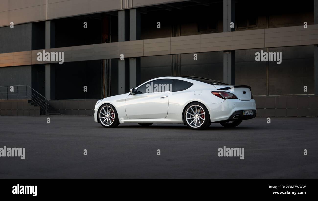 white Hyundai Genesis Coupe in front of dark grey wall. Rear three ...