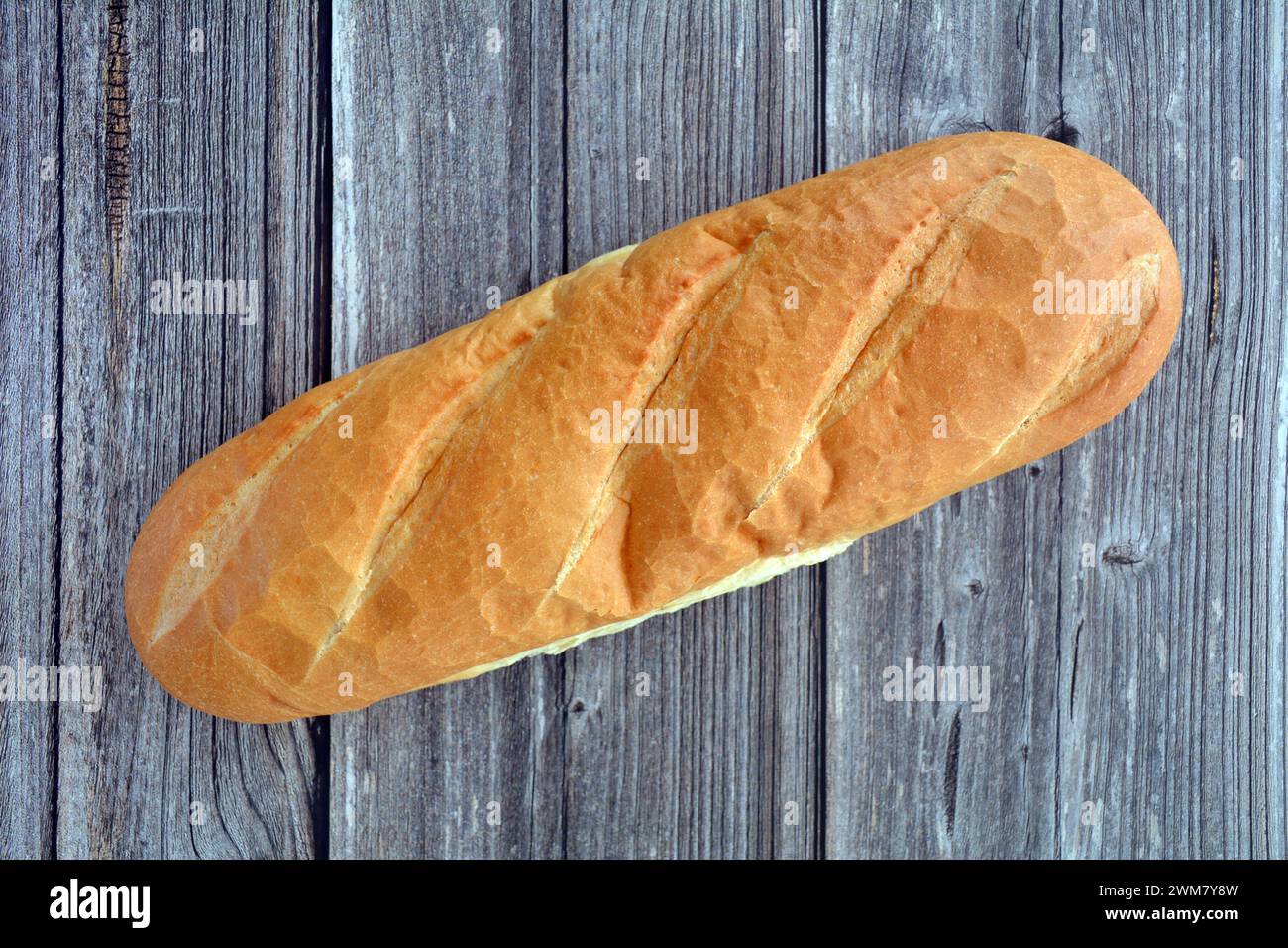 Fresh baked crusty golden French loaf on rustic grey wood background in ...