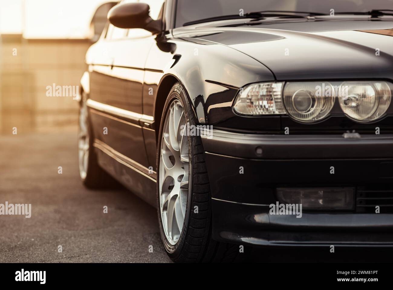 Black BMW 7-series (E38) sedan at sunset. Close up view of front right ...