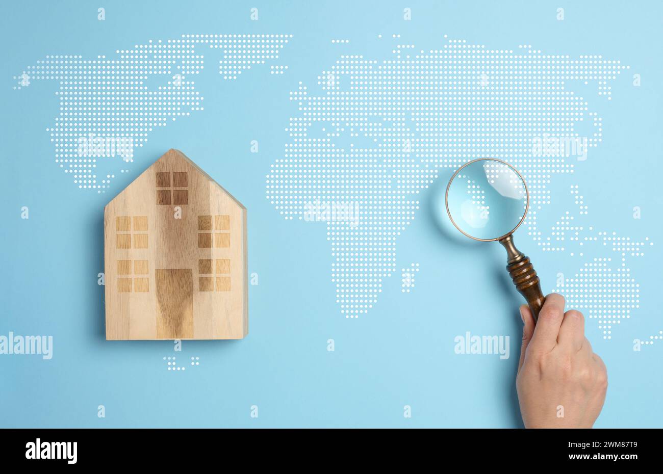 Wooden house on a world map background with a person's hand holding a ...