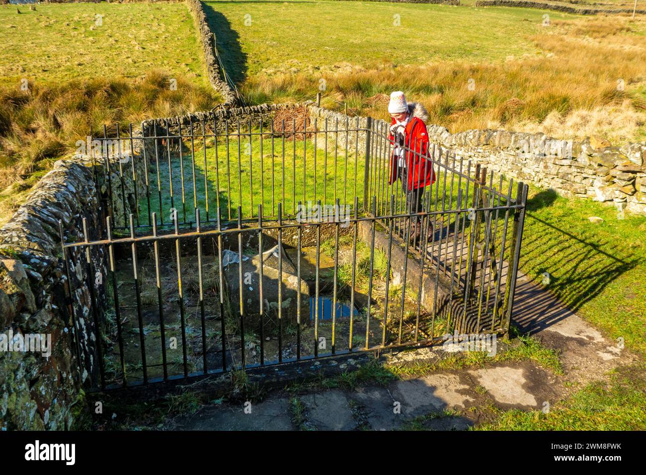Woman walking in the Peak District stopped to look at Mompessons Well ...