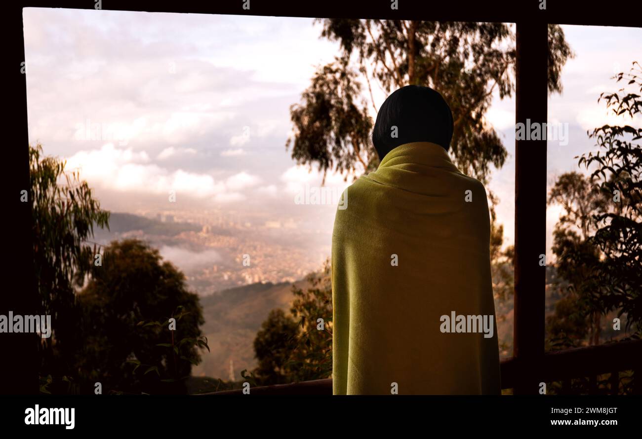 Back view of peaceful woman with blanket standing alone and enjoying ...
