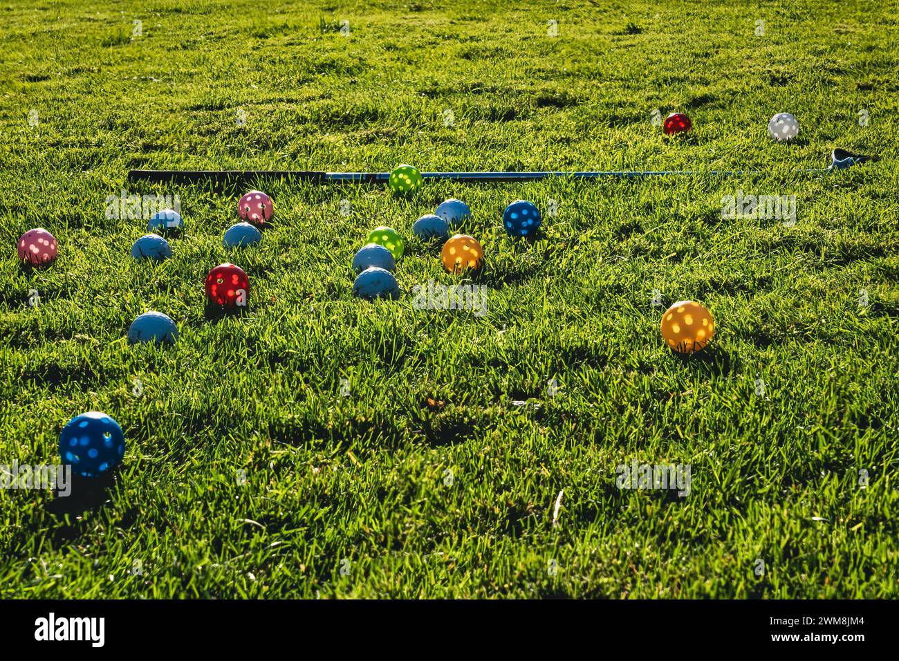 Many light colorful practicing plastic golf balls with holes and one ...