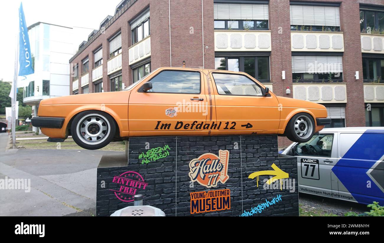 Orange car with two front ends as an welcome ad sign to Halle 77 museum ...