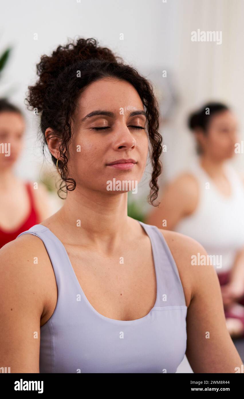 Female yoga trainer guiding a group of women to meditate in lotus ...
