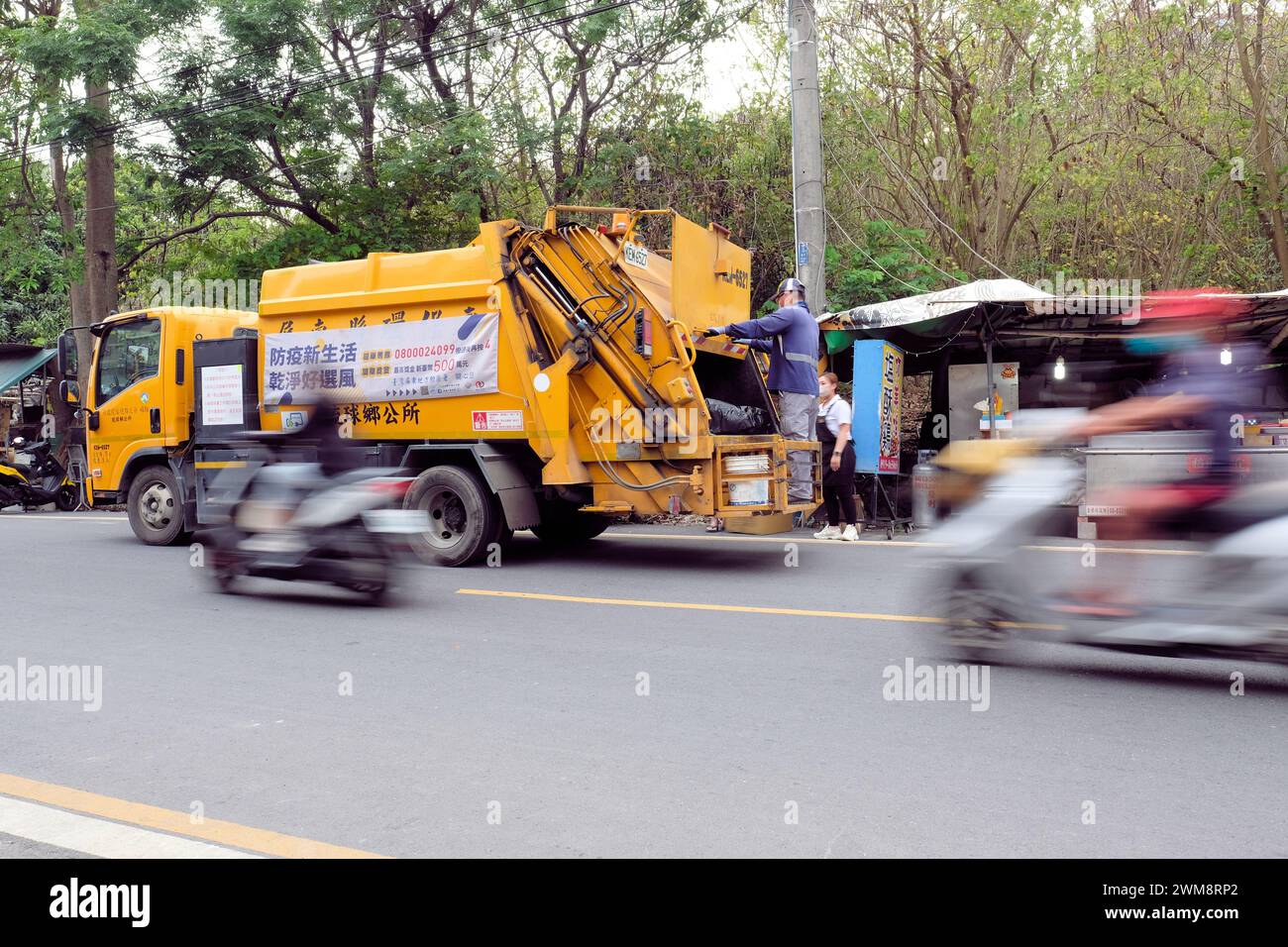 Trash collecting garbage truck with worker riding in back on Zhongzhan ...