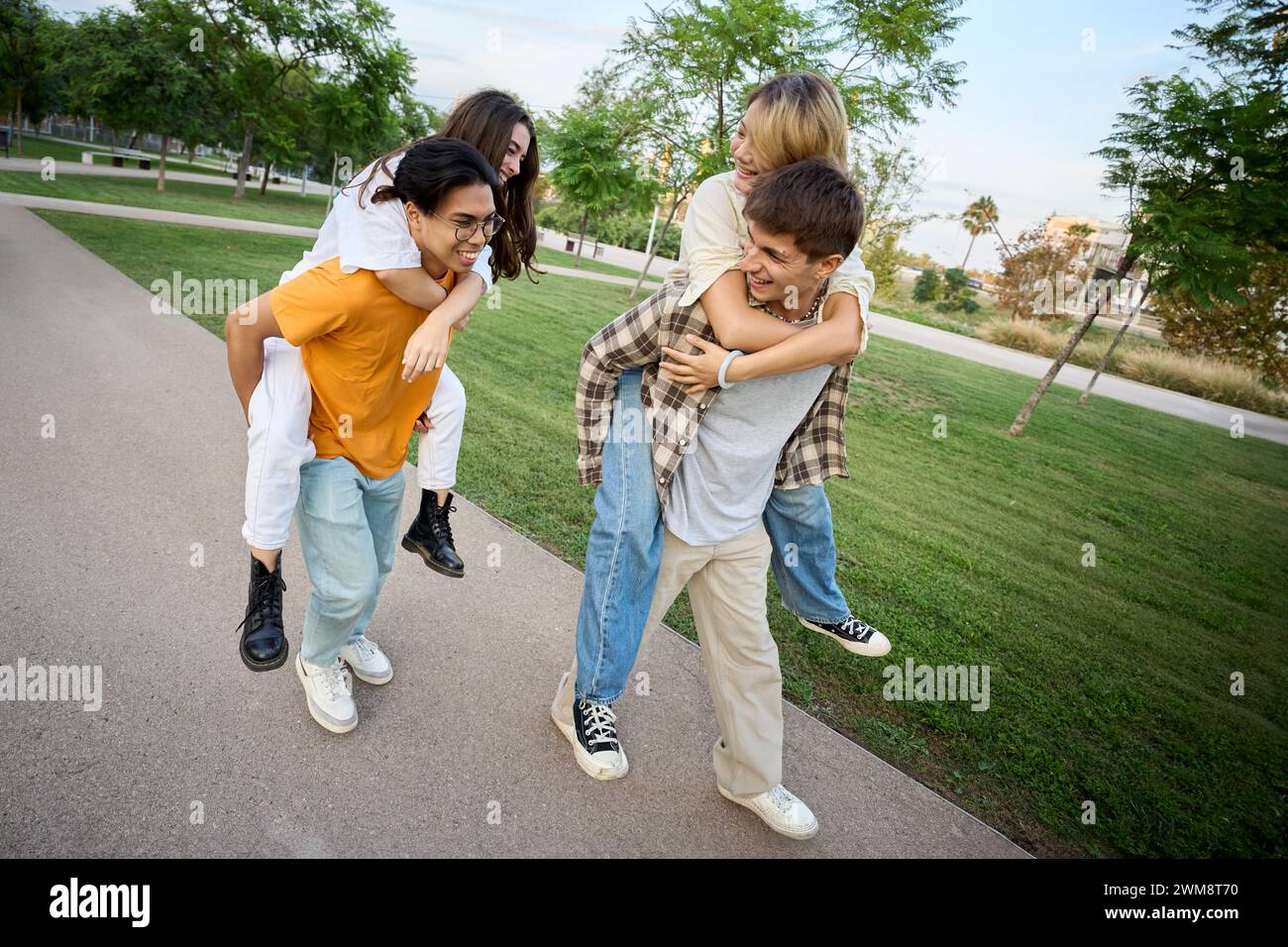 Cheerful multiracial couple doing a race in piggyback. Group of people ...