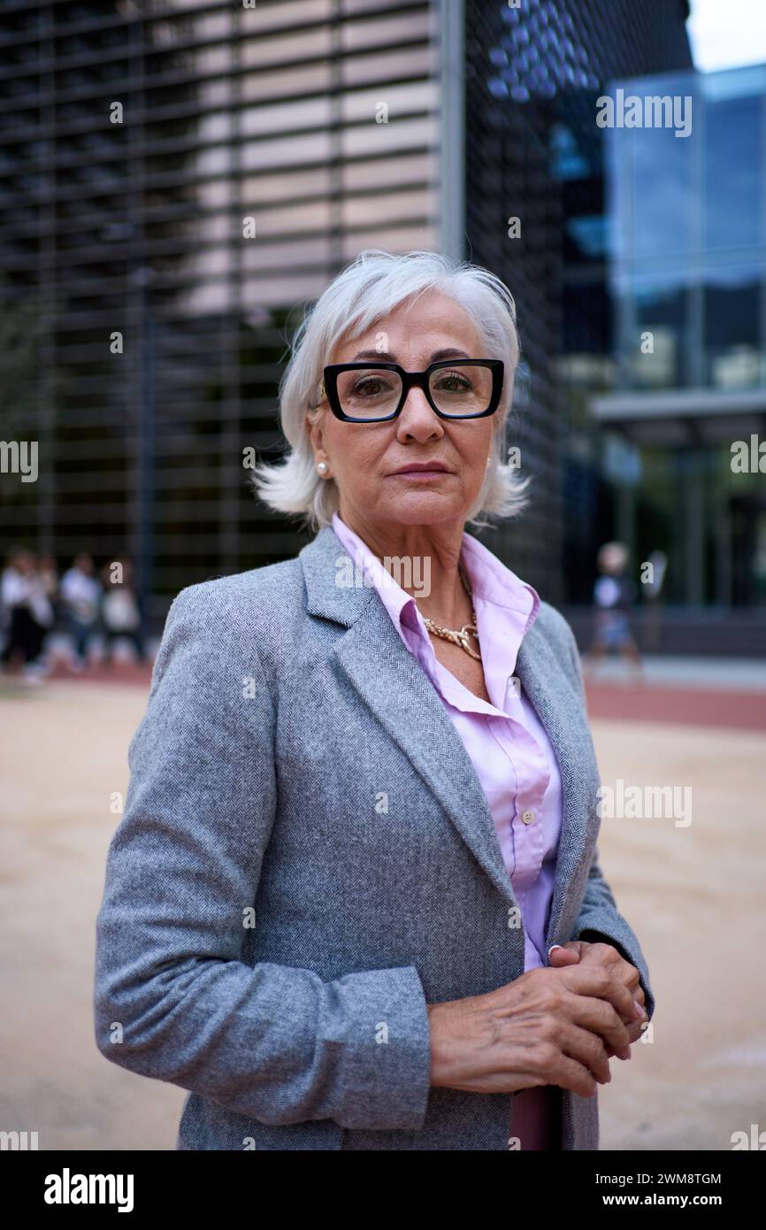Successful and serious mature business gray woman with hands clasped at ...