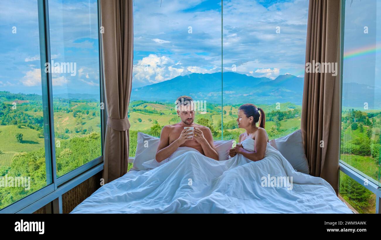 a couple of men and women laying in bed with open widows looking out ...