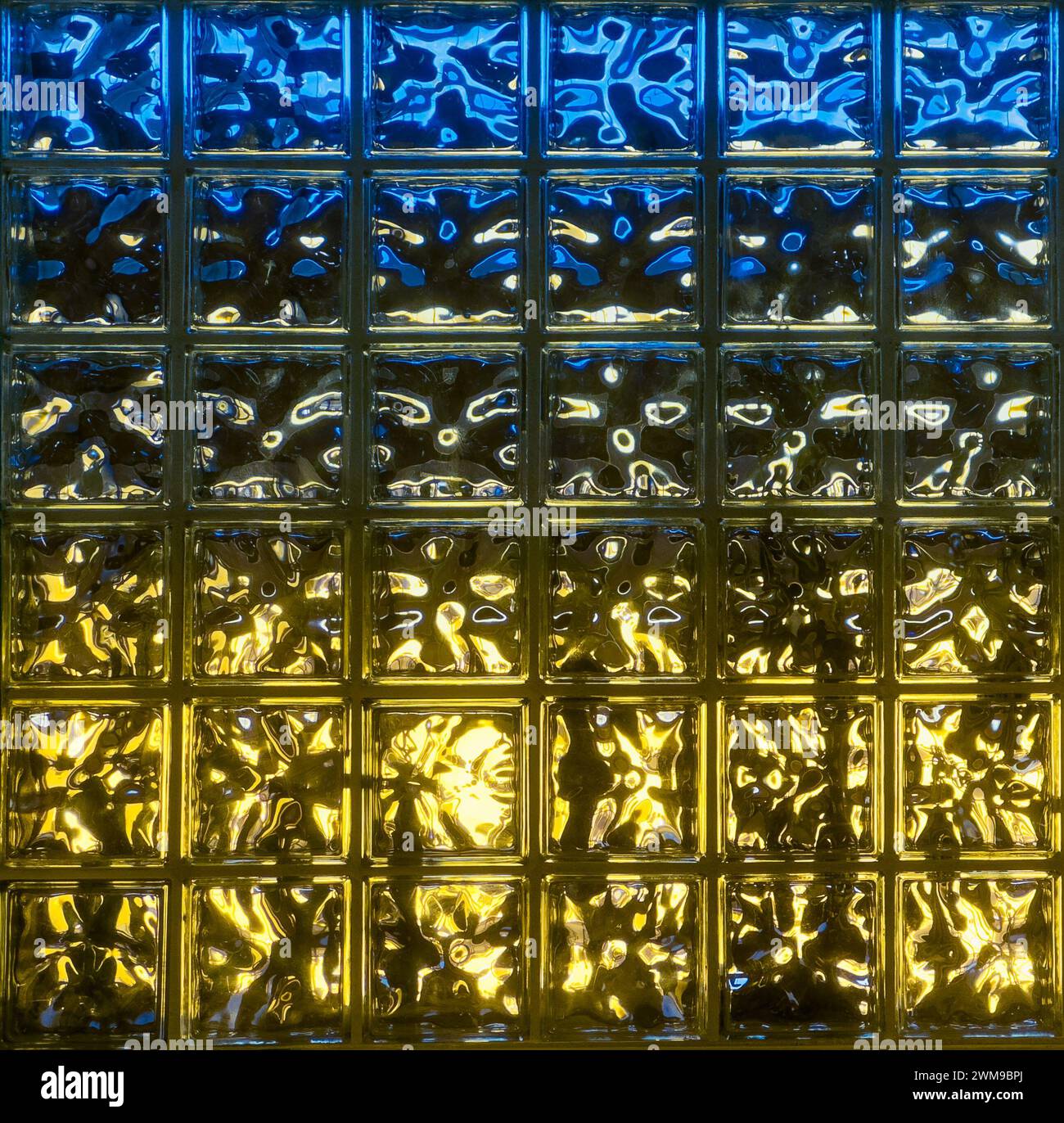 Light Passing Through A Wall Of Glass Blocks Creates A Colorful Blue And Yellow Wavey Pattern