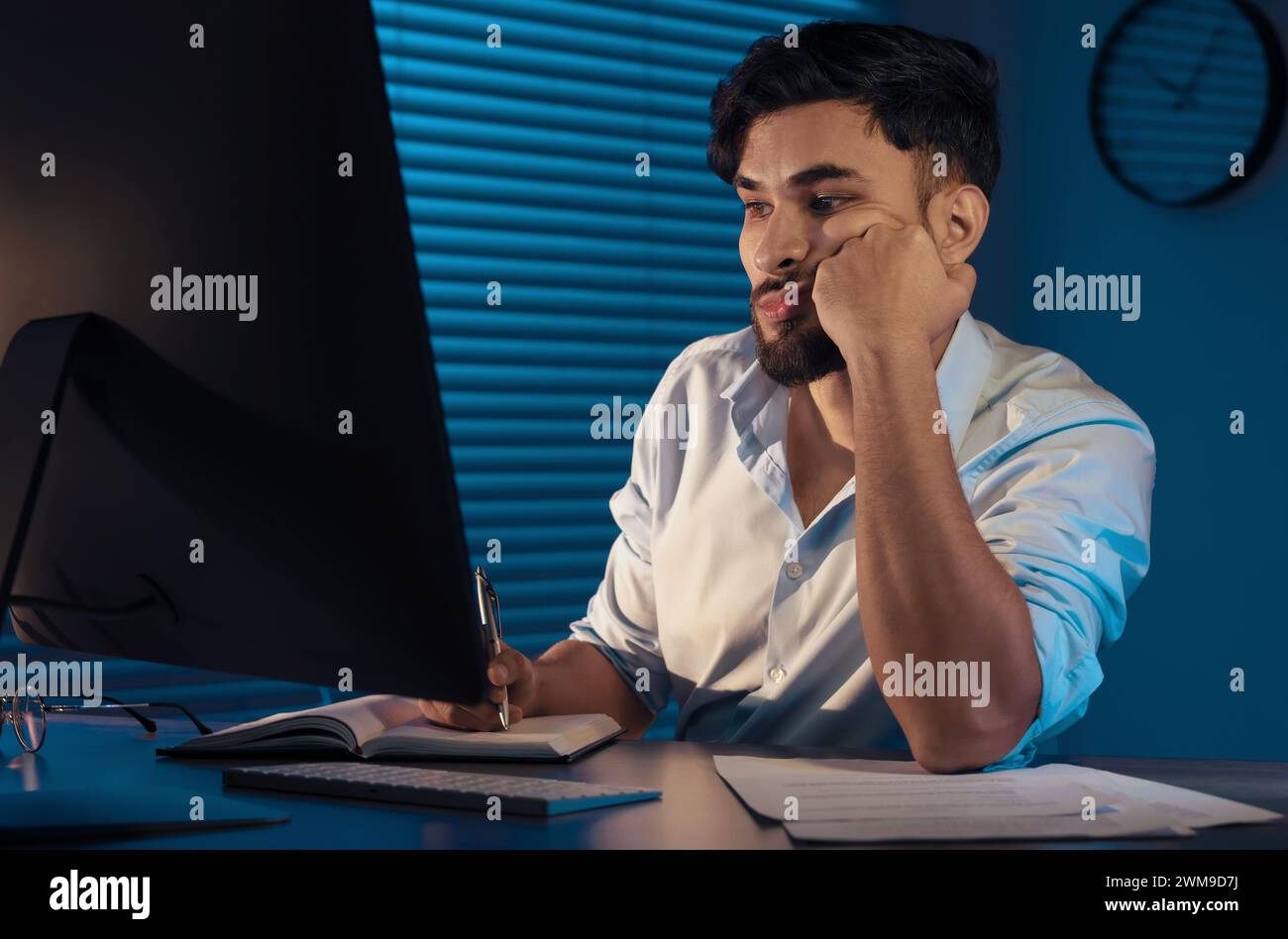 Tired young man working late in office Stock Photo - Alamy