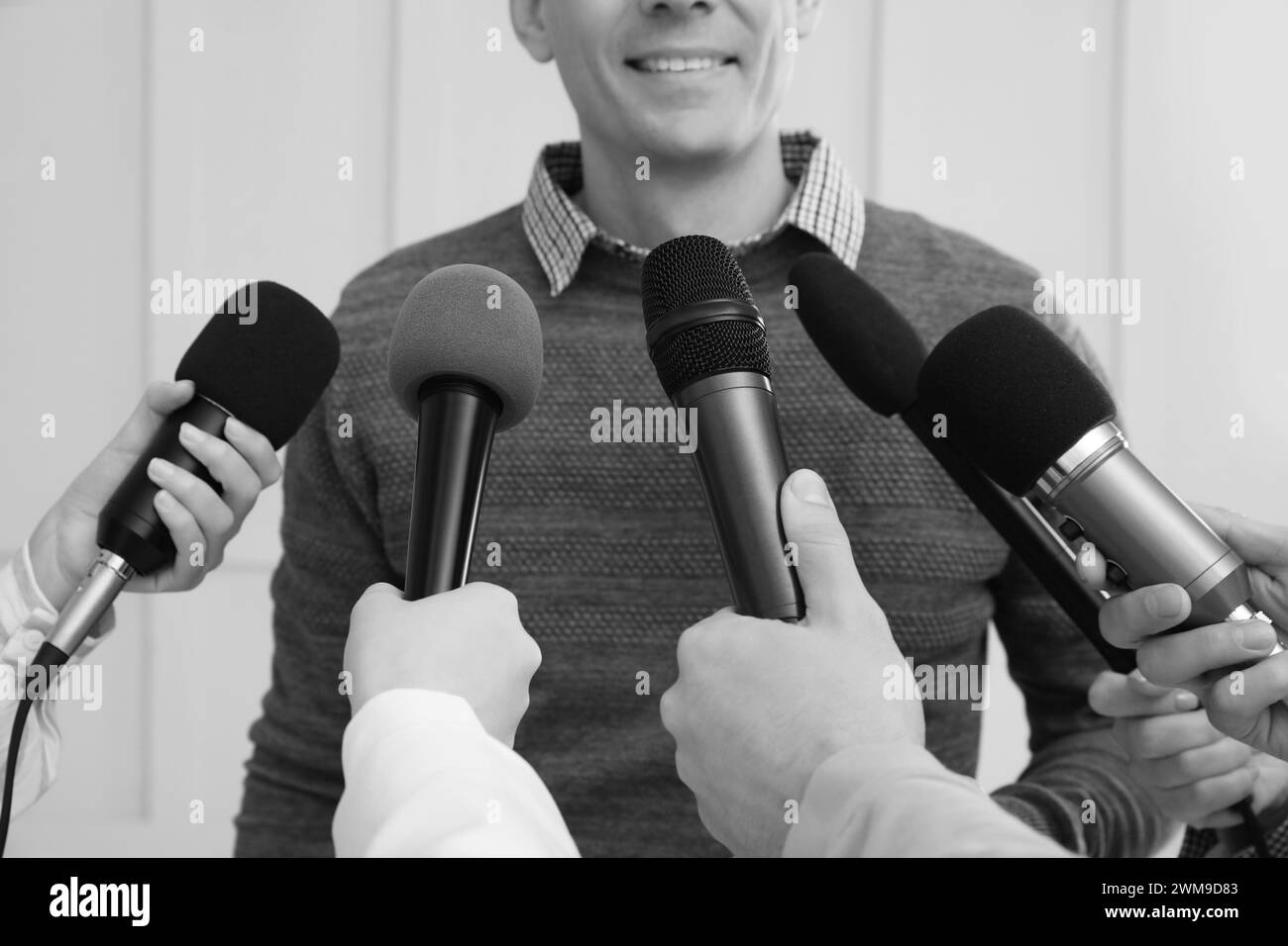 Man giving interview to journalists indoors, closeup. Black and white ...