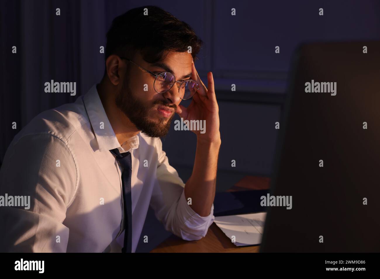 Tired young man working late in office Stock Photo - Alamy