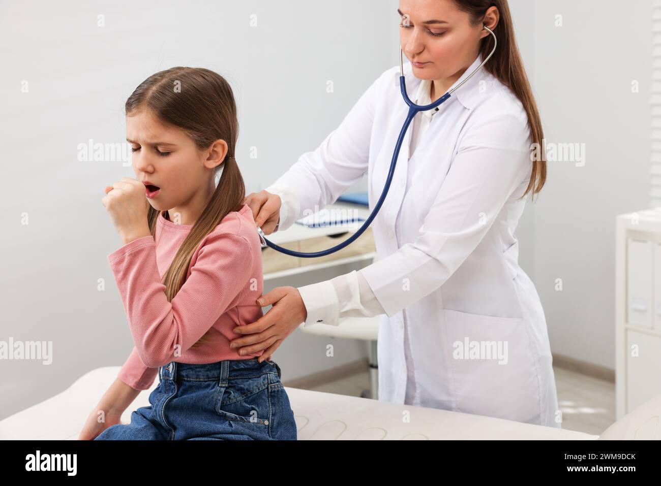Doctor examining coughing girl in hospital. Cold symptoms Stock Photo ...