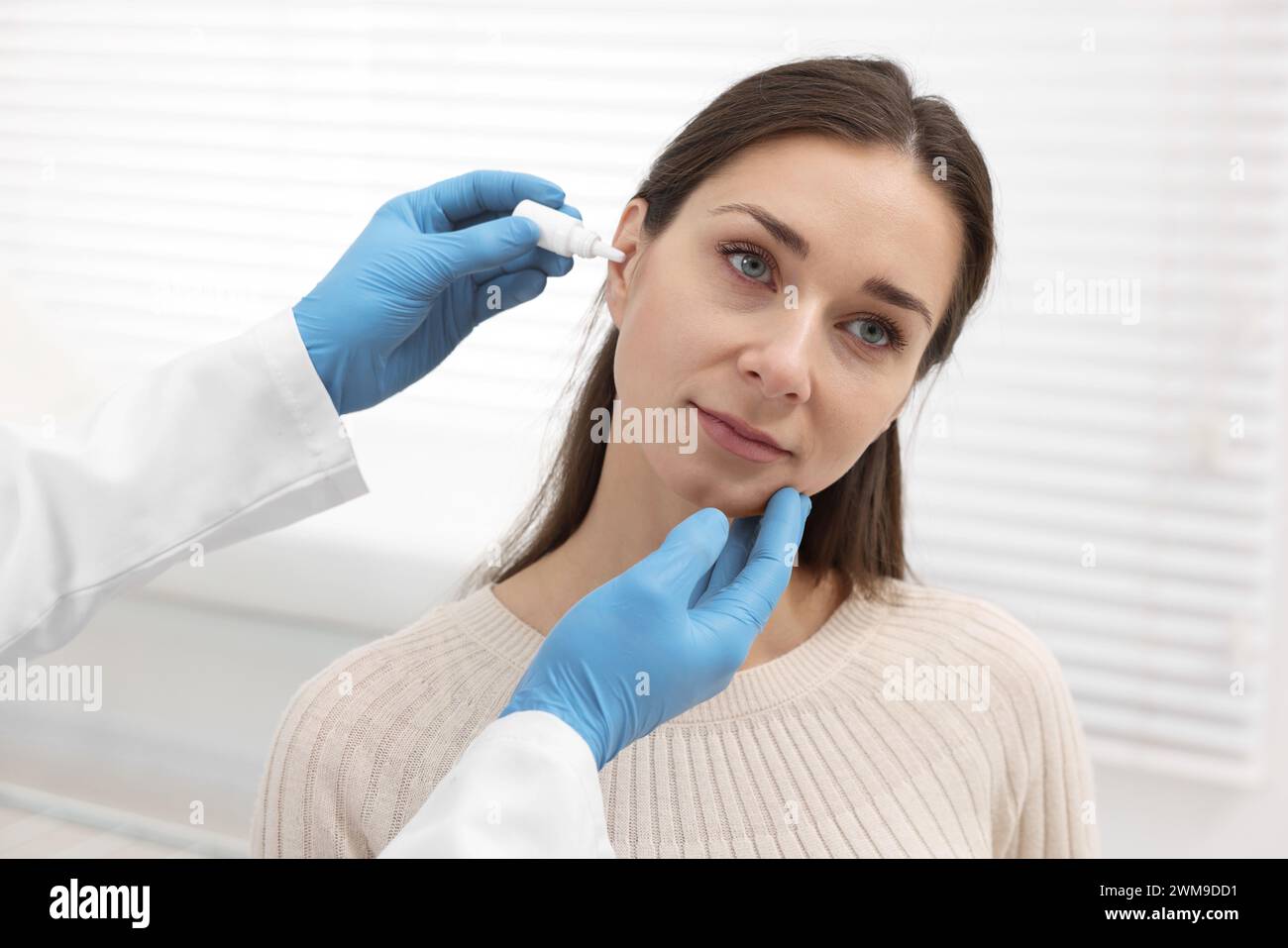 Doctor applying medical drops into woman's ear indoors Stock Photo - Alamy