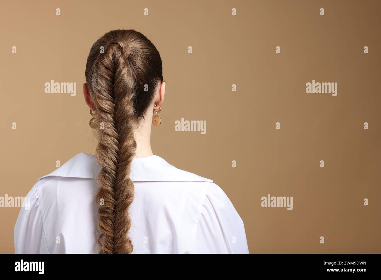 Woman with braided hair on brown background, back view. Space for text ...