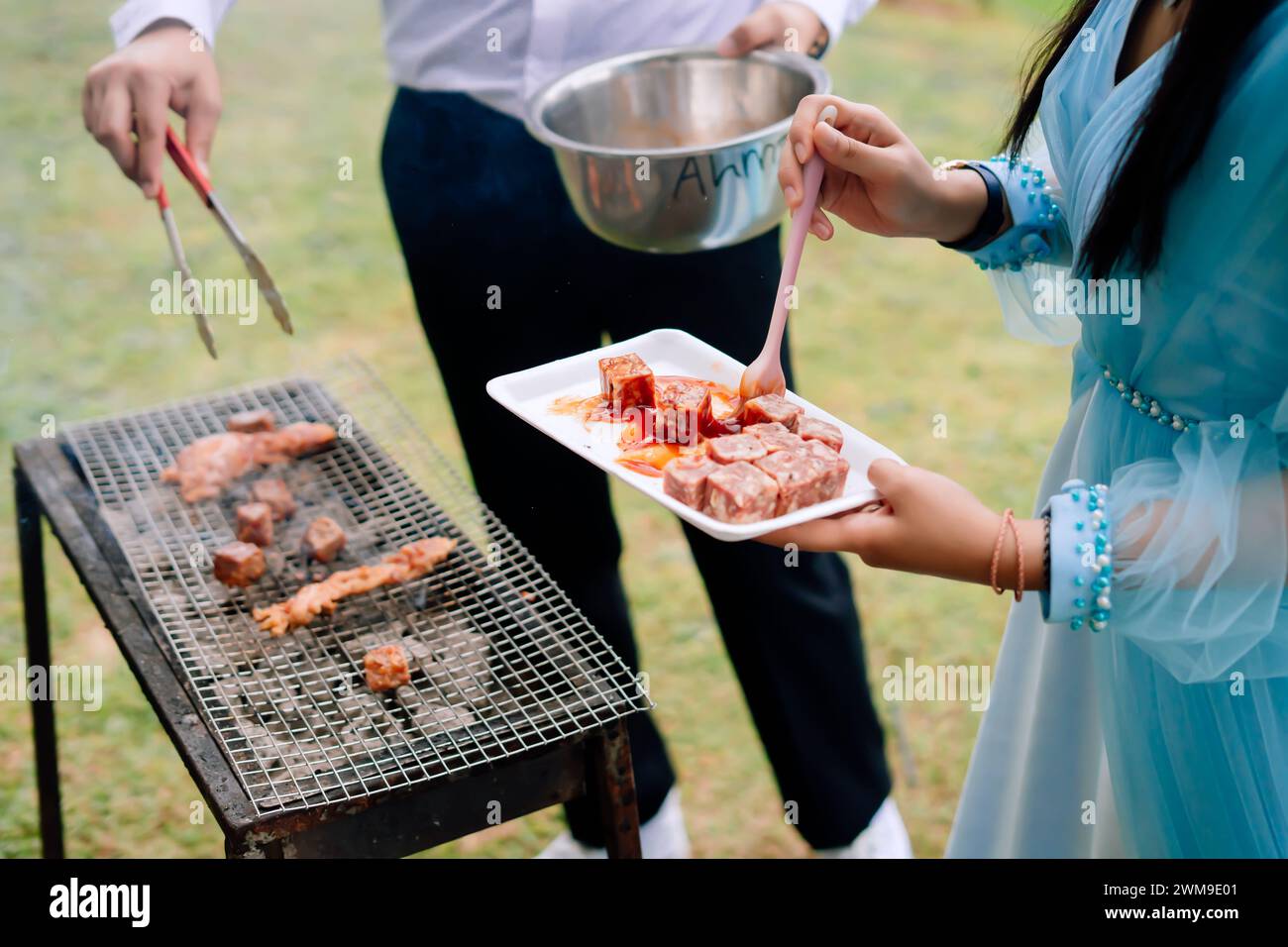 A couple grills some cutlets on a charcoal grill during spring. Garden ...