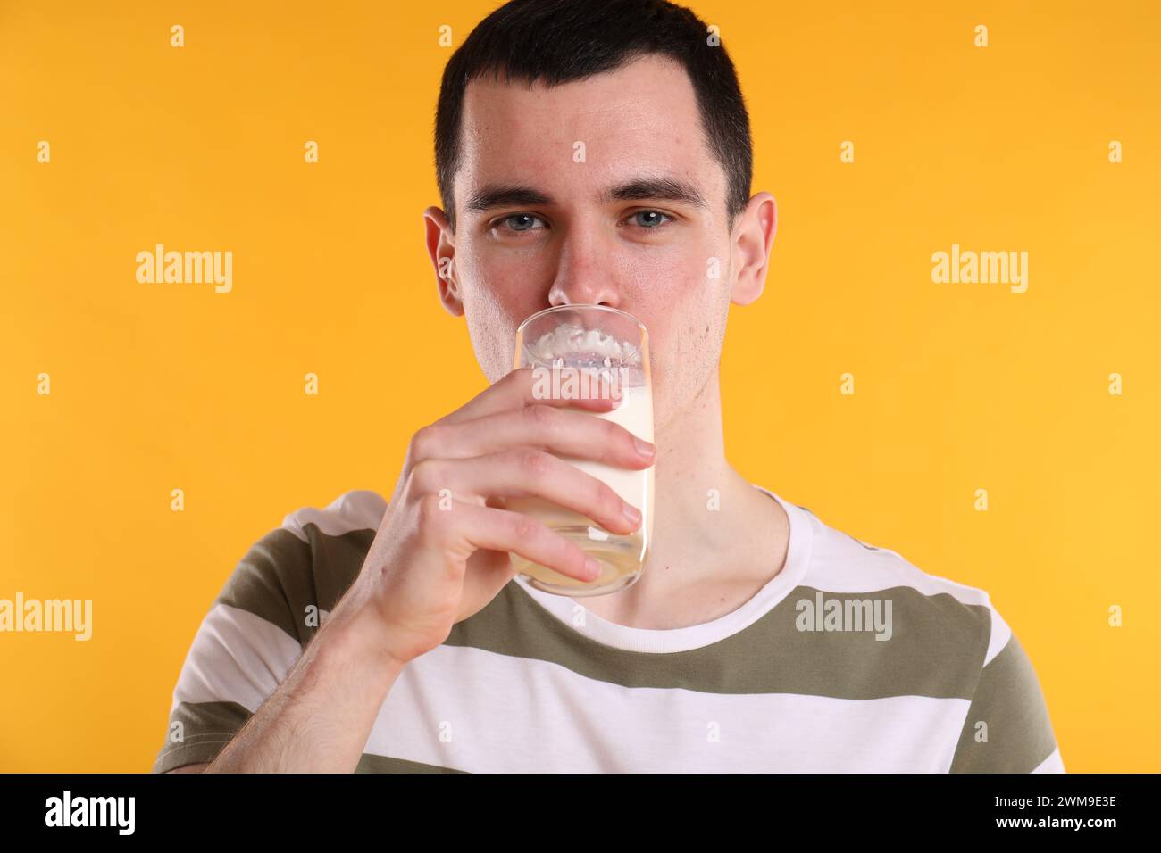 Milk mustache left after dairy product. Man drinking milk on orange ...
