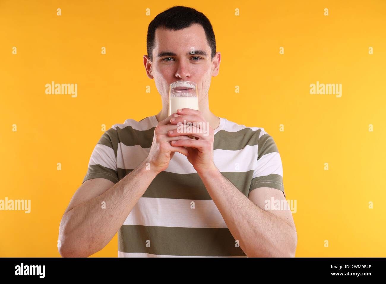 Milk mustache left after dairy product. Man drinking milk on orange ...