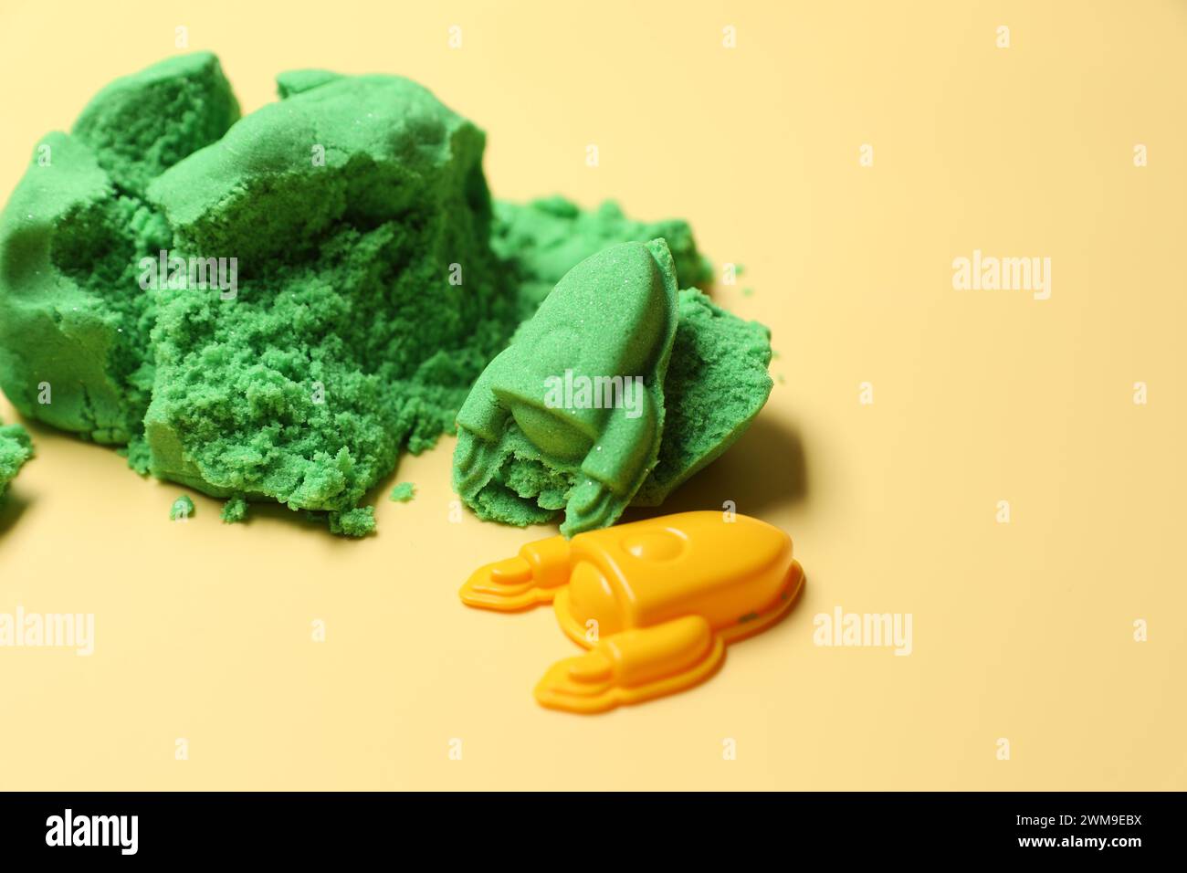Bright kinetic sand and plastic toys on beige background, space for ...