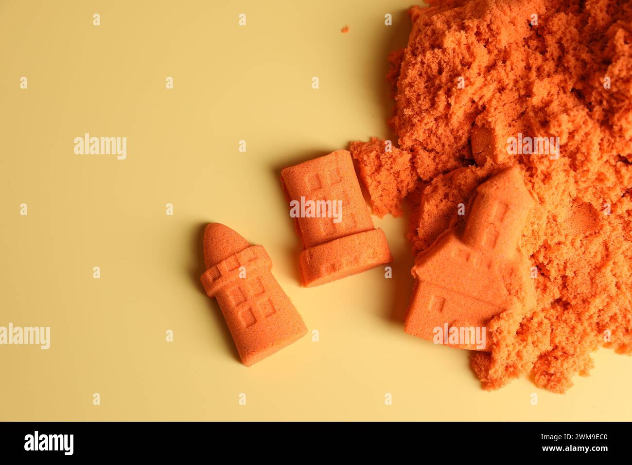Castle figures made of orange kinetic sand on beige background, flat ...