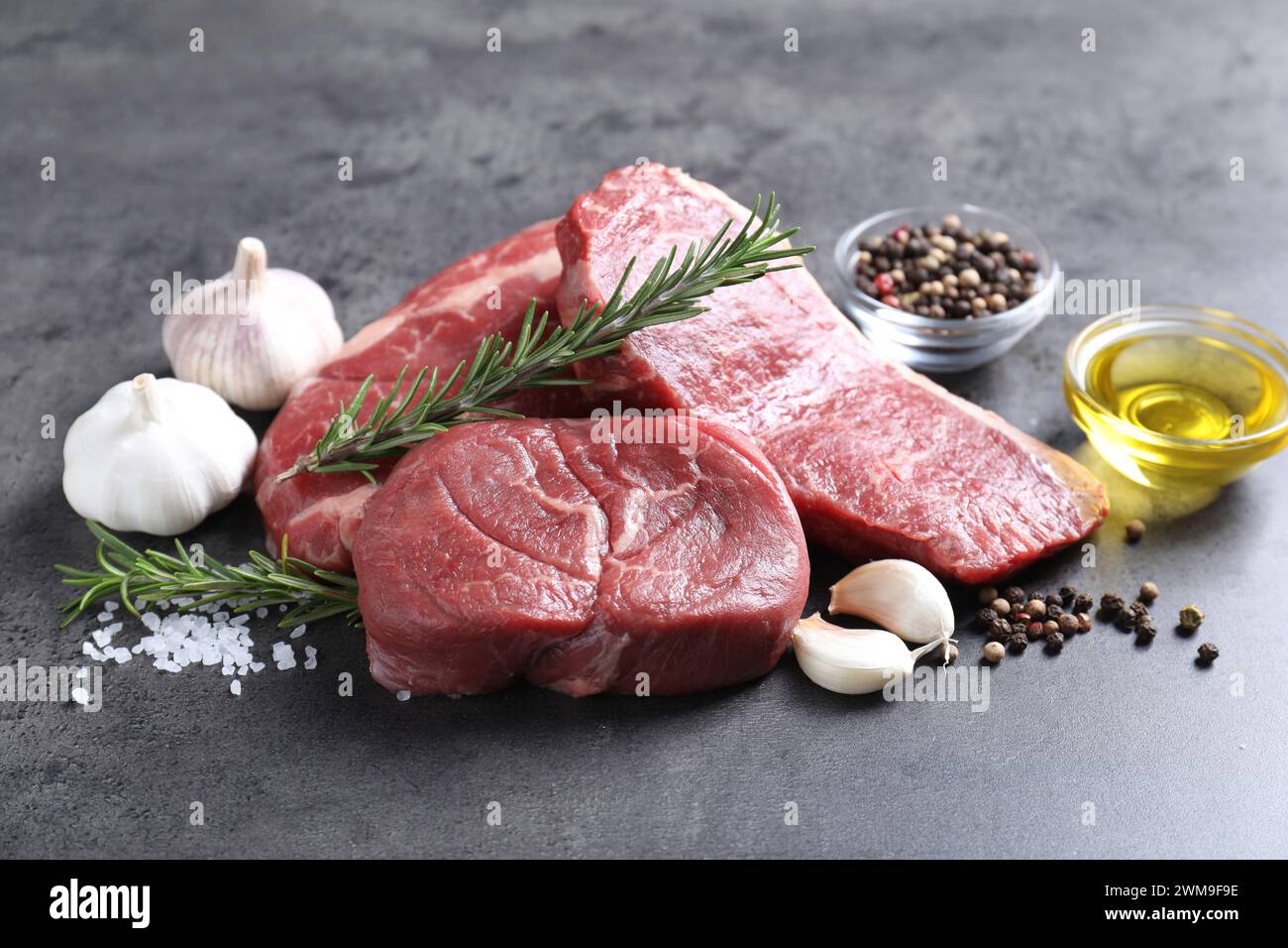 Raw beef steaks, oil and spices on grey table Stock Photo - Alamy