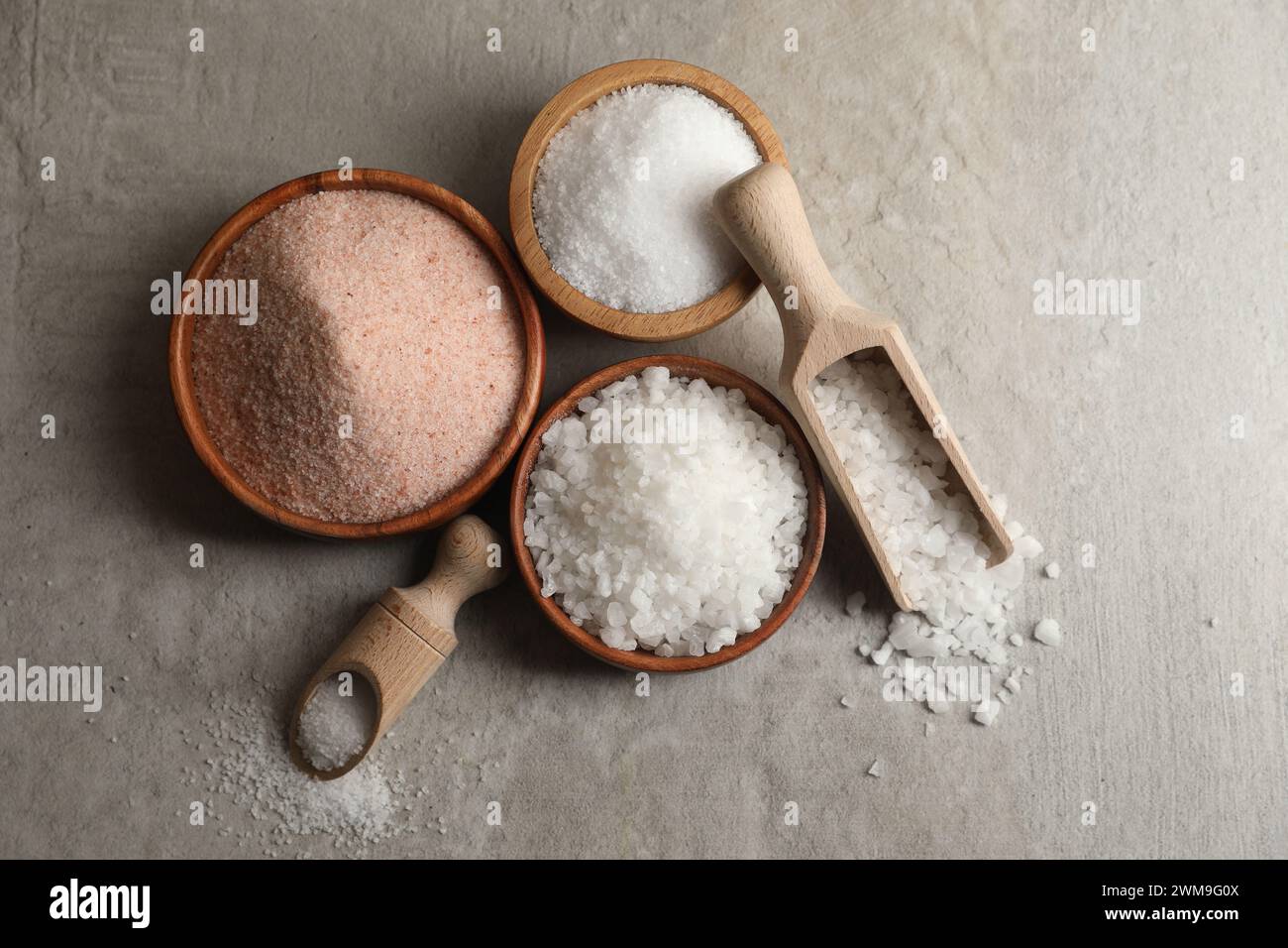 Different natural salt on grey textured table, flat lay Stock Photo - Alamy