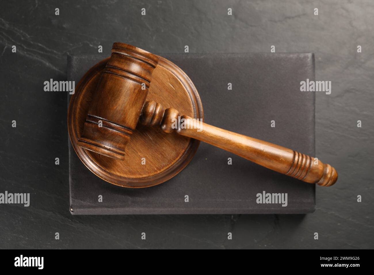 Wooden gavel, sound block and book on dark textured table, top view ...