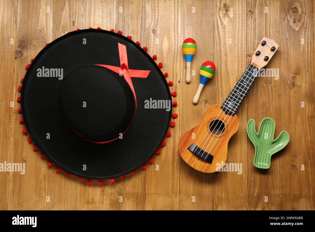 Mexican sombrero hat, maracas, toy cactus and guitar on wooden ...