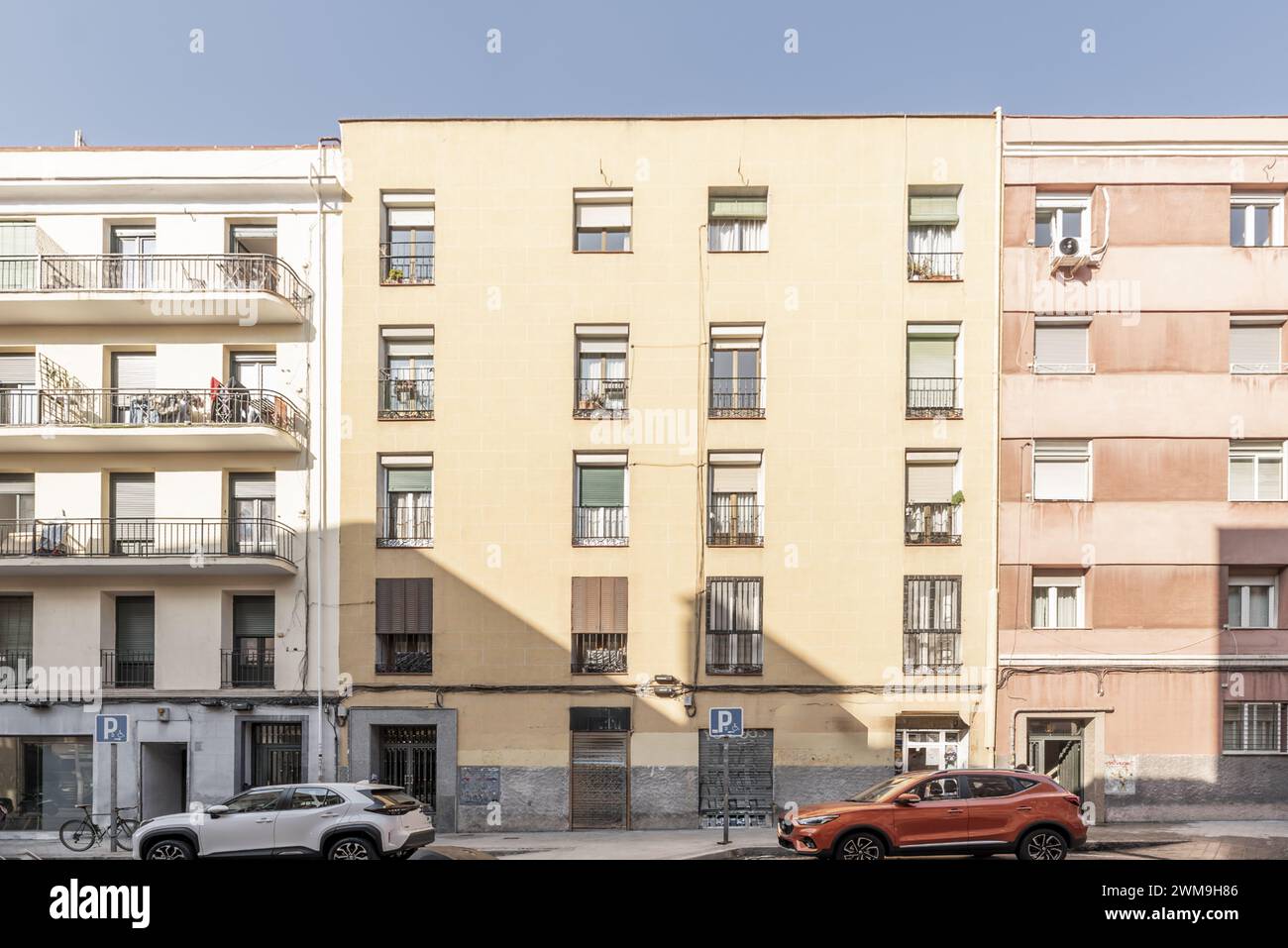 Facades of residential buildings with parked vehicles and parking areas ...
