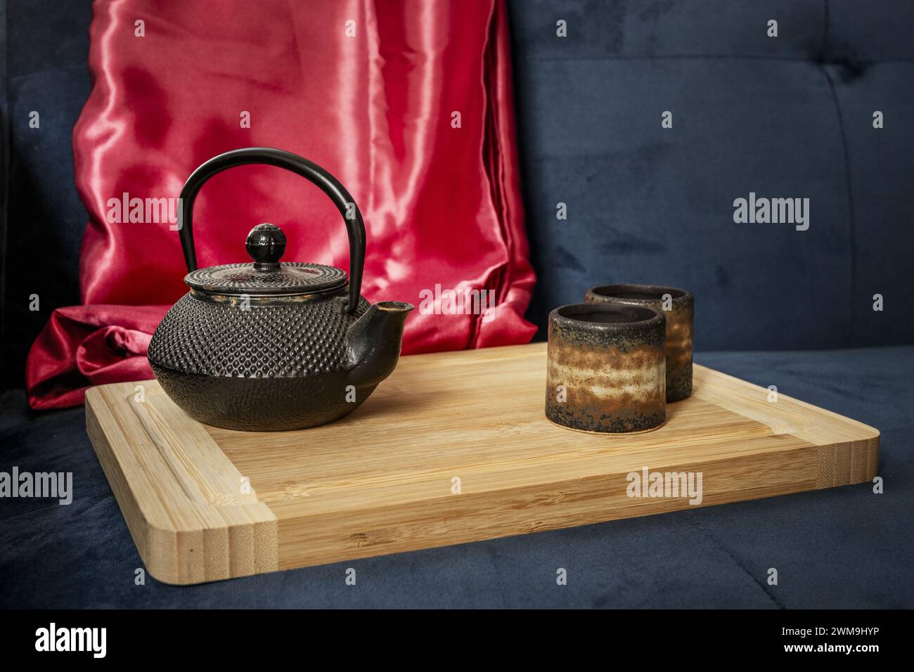 An Asian style black wrought iron jug with some tea glasses next to it ...