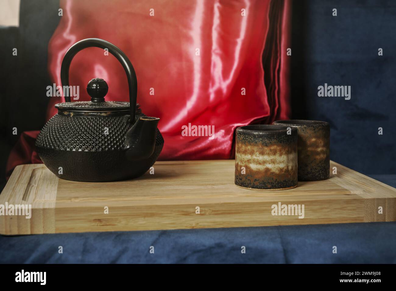 An Asian style black wrought iron jug with some tea glasses next to it ...