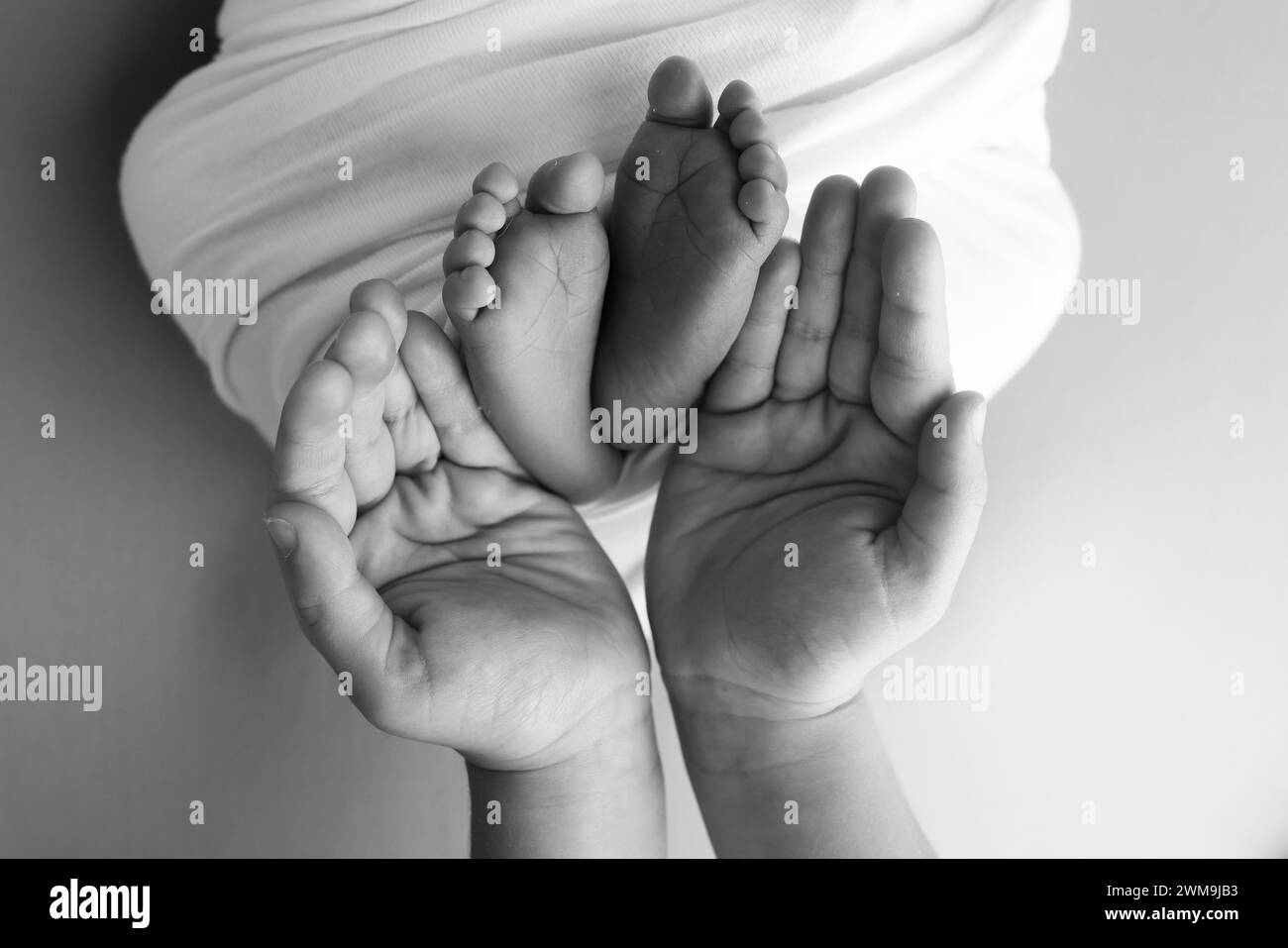 The palms of the father, the mother are holding the foot of the newborn ...