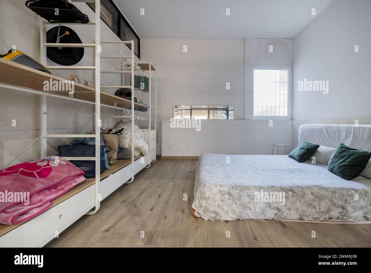 Half empty room with a wall covered with white and wooden shelves, a ...