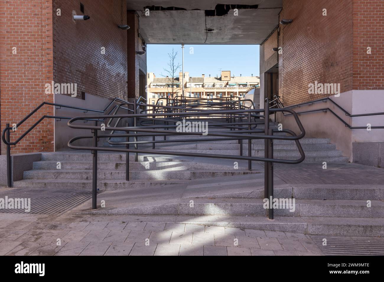 Passage with stairs to descend a ramp with a tubular metal railing ...