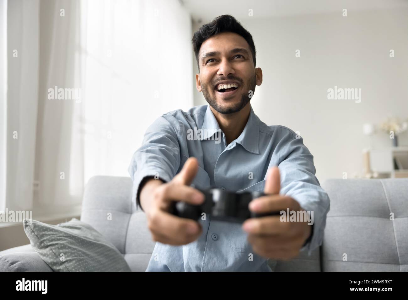 Excited Indian man holding gamepad controller playing video games Stock ...