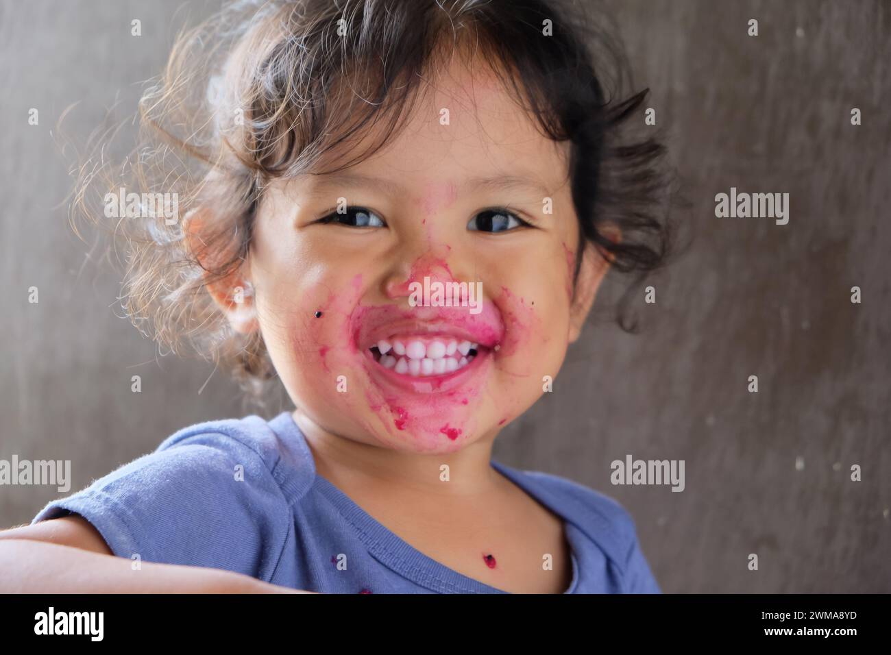 Close-up of a cute curly boy enjoying exotic dragon fruit with a red ...