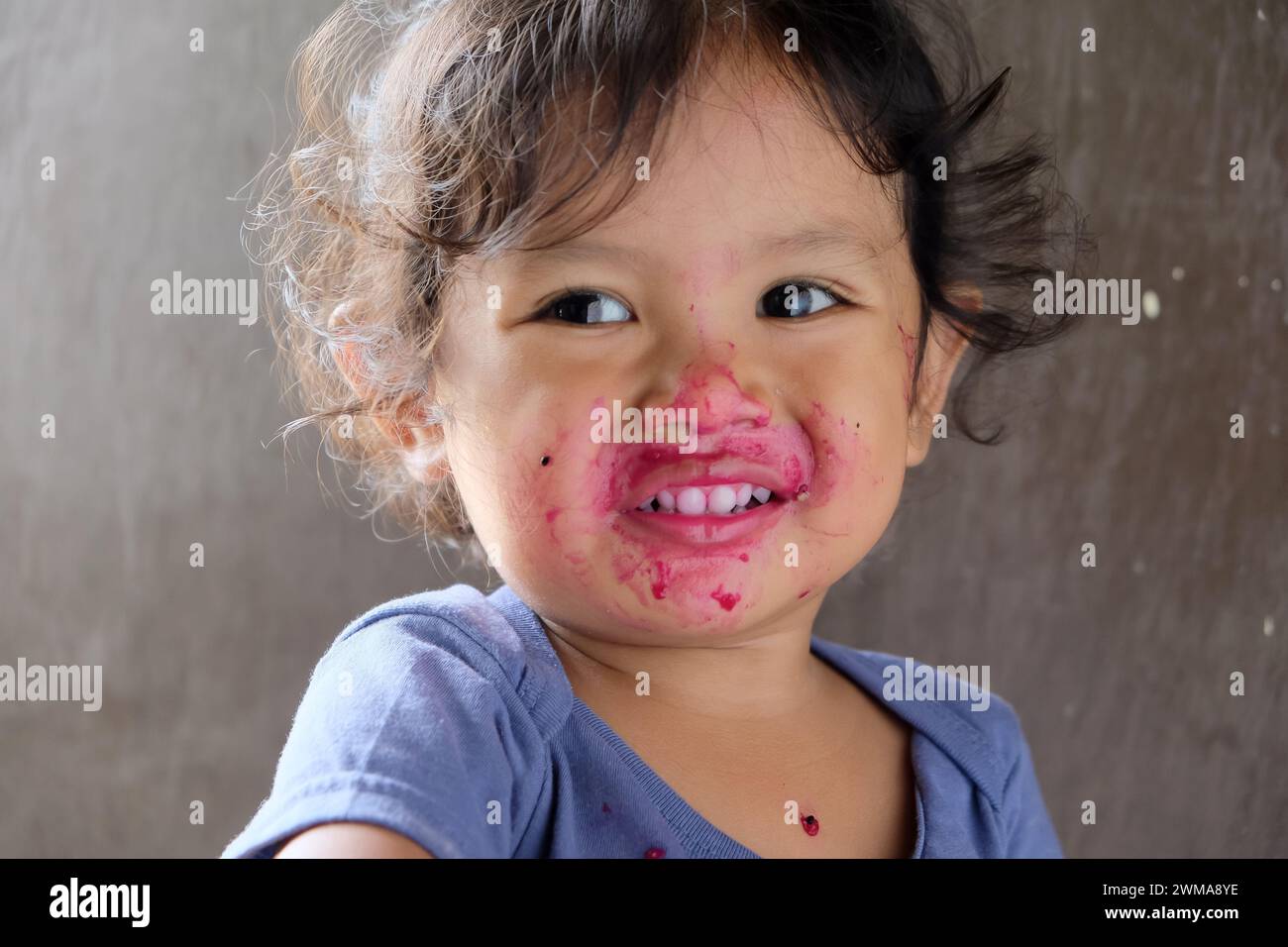 Close-up of a cute curly boy enjoying exotic dragon fruit with a red ...