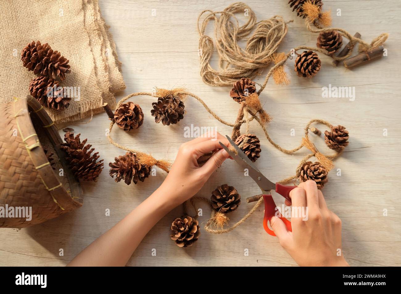 Woman's hands make wall decorations from pine cones and jute rope Stock ...