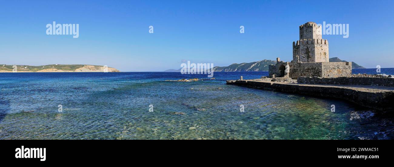 An old stone tower on a coast with crystal clear sea water under a wide ...