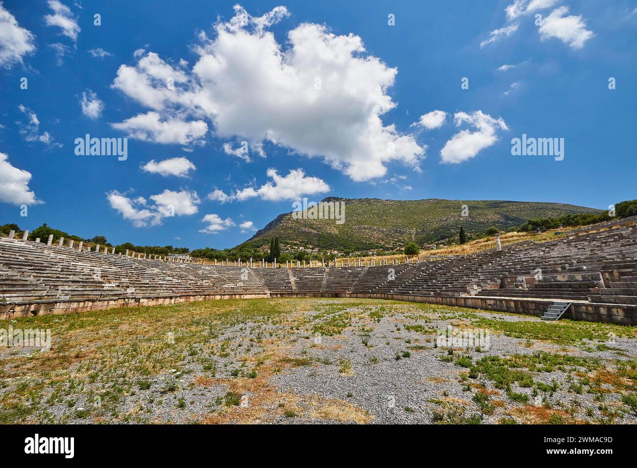 Ancient stadium with many rows of seats, surrounded by grass and sky ...