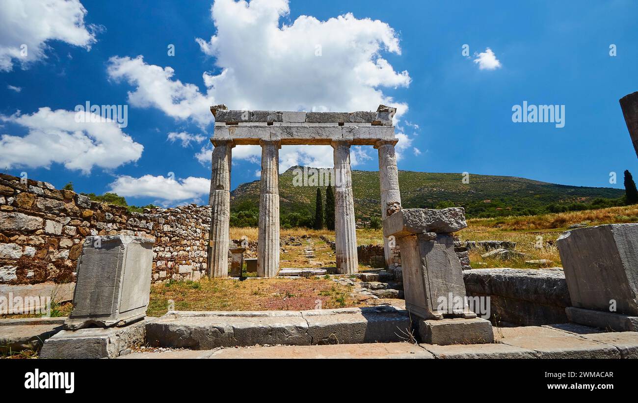 Ancient portico gate in the sunlight under a light blue sky with clouds ...
